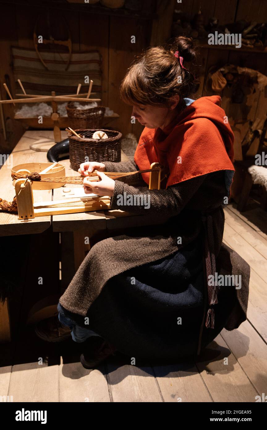 A woman dressed the part of a Viking weaver at her workbench in the ...