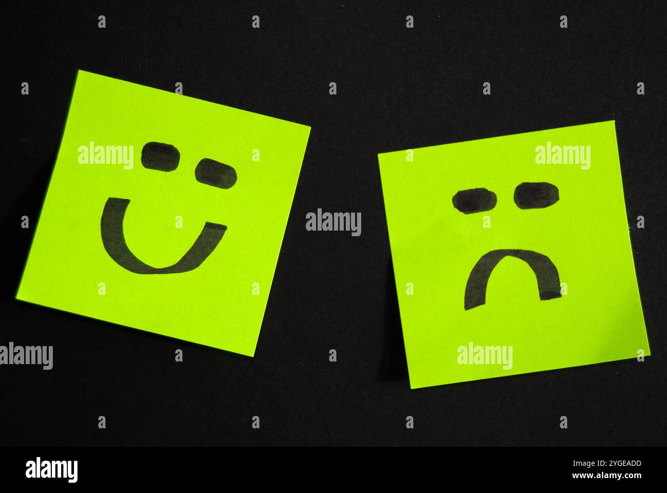 A conceptual photo showing two green sticky notes: one with a smiley ...