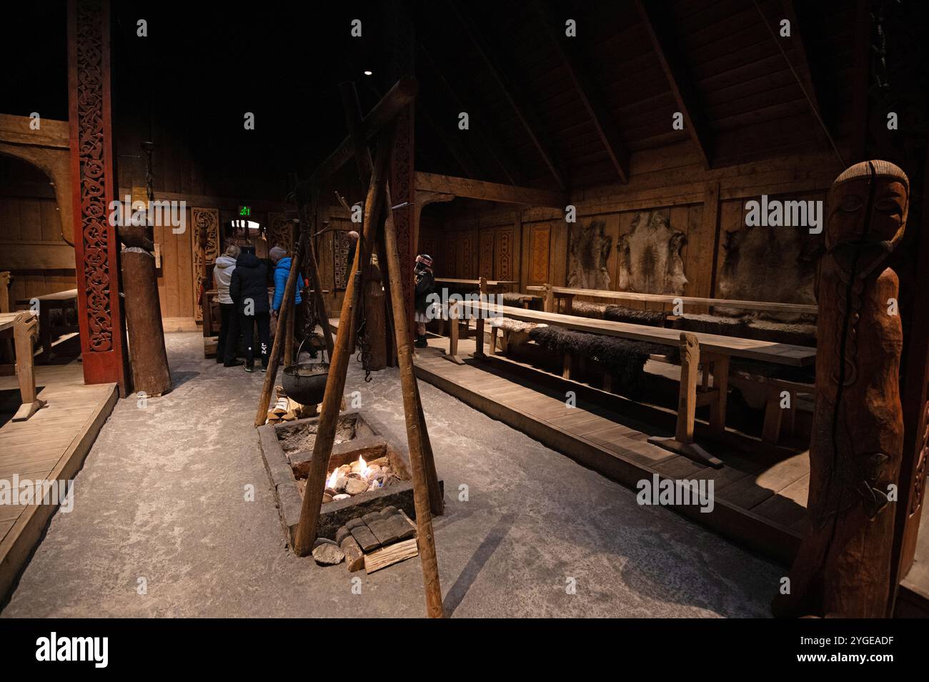 The long banqueting hall with some cooking pots on a log fire inside ...