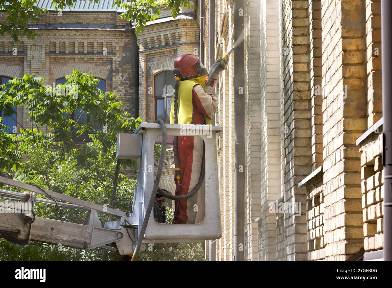 Worker using a lift to clean the exterior walls of a historic building ...