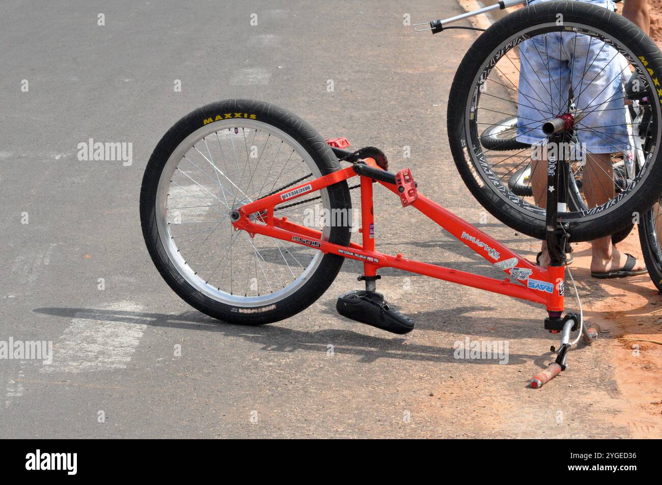 Orange bicycle upside down on asphalt with young man next to it Stock ...