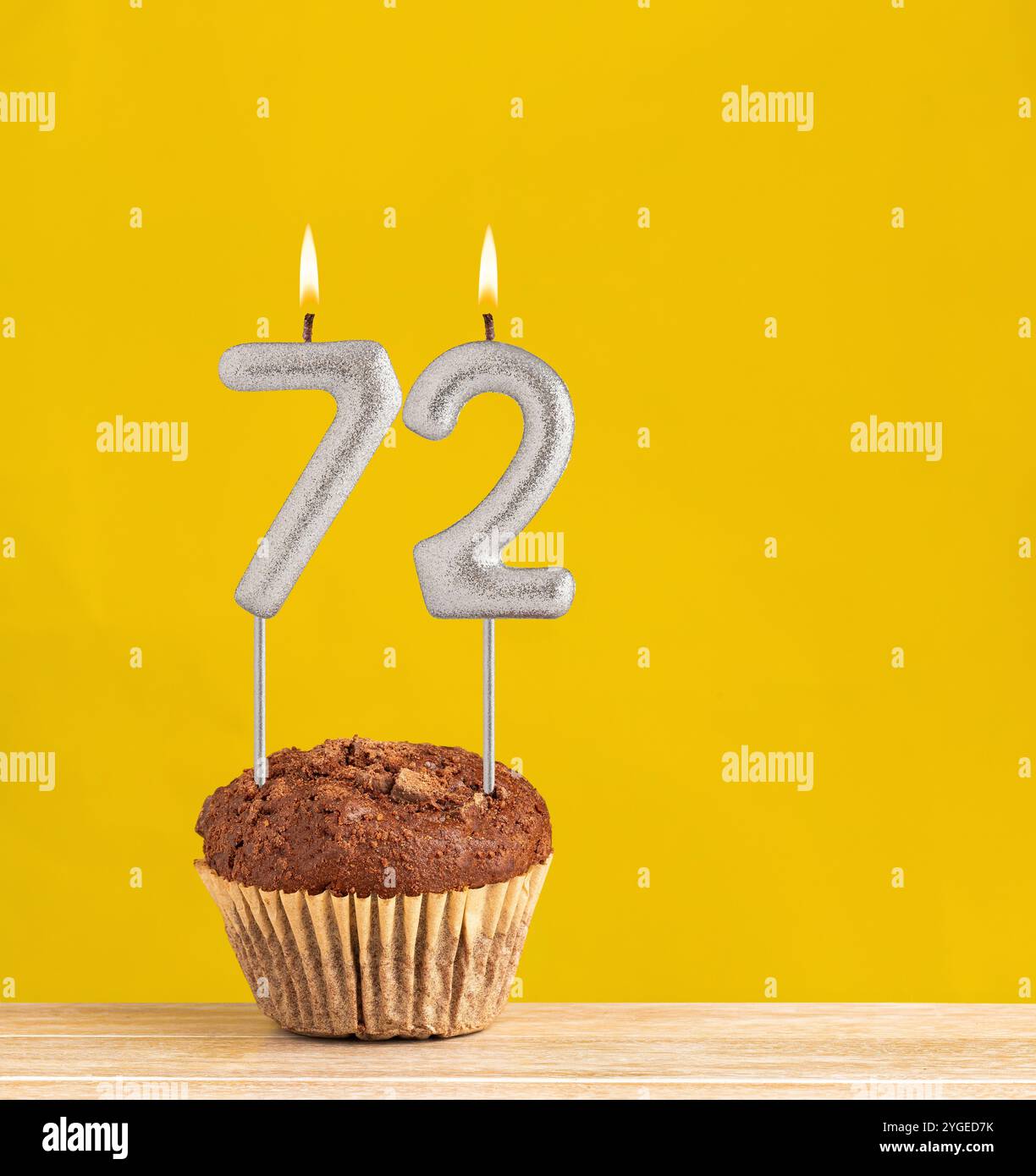 Chocolate cupcake with number 72 candle - Birthday on a yellow ...