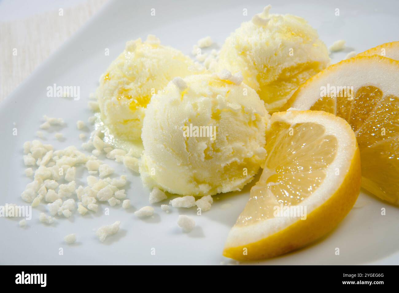 Three scoops of lemon ice cream with lemon slices close up, on a white ...