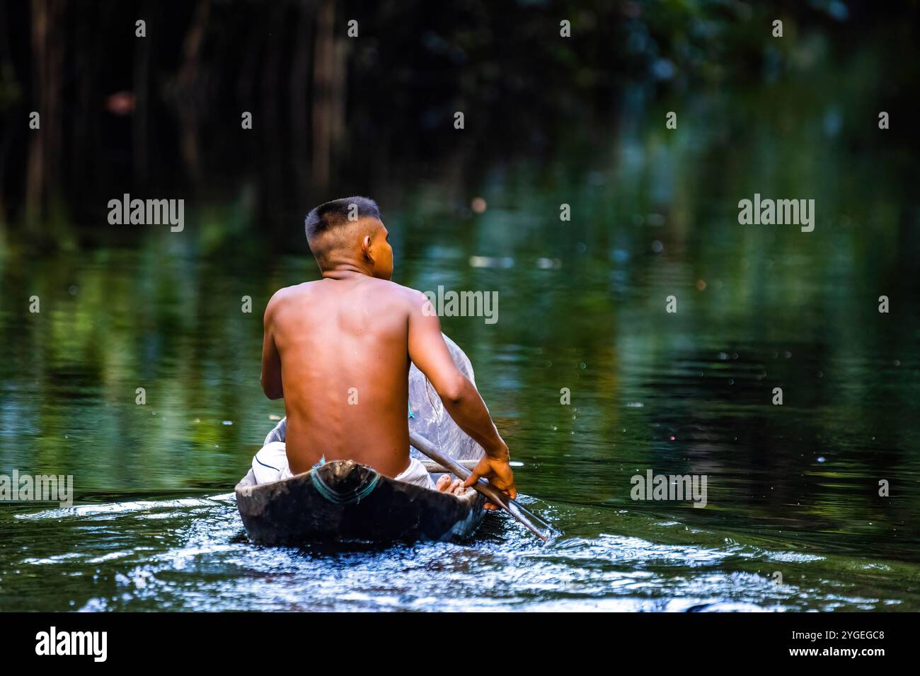 Native tribal man swimming in amazonia rainforest in handmade boat ...