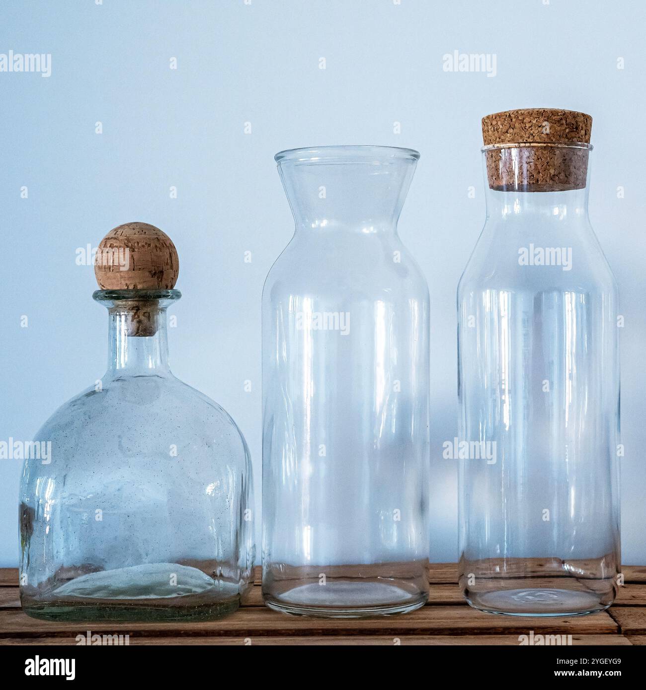 Three glass bottles of different shapes on a white background. Empty ...