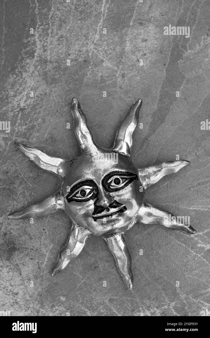 Monochrome image of model of sun with big face and flickering rays ...