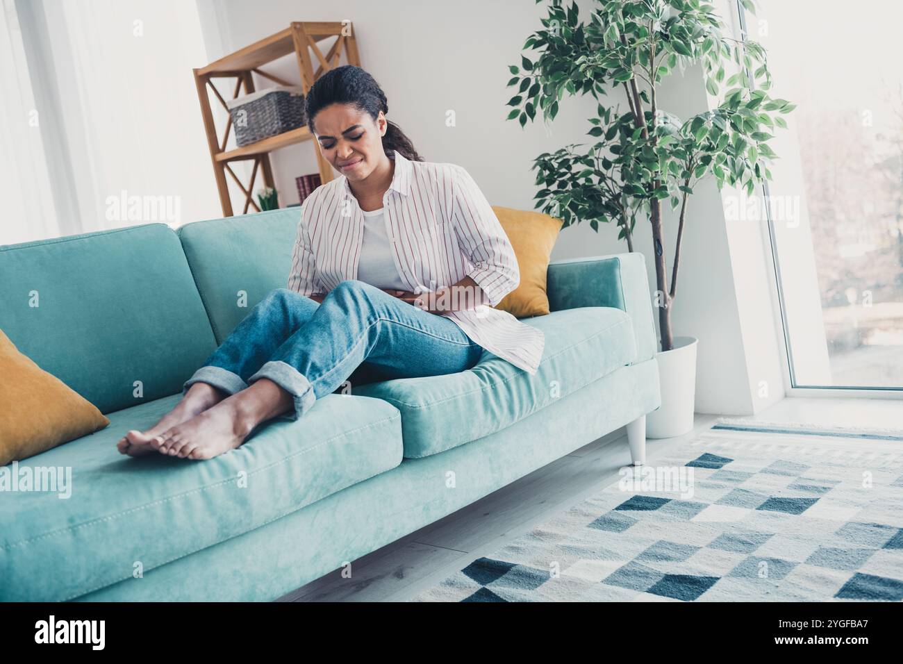 Full size photo of pretty young girl sit couch stomach ache wear shirt ...