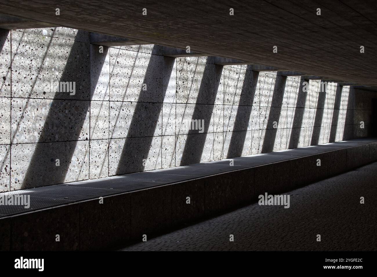 Concrete wall with angled light and shadow patterns, creating a ...