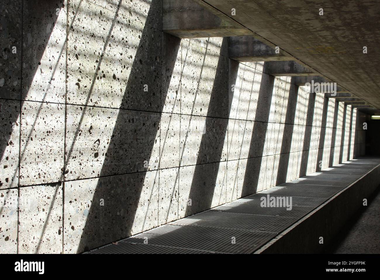Concrete wall with angled light and shadow patterns, creating a striking geometric effect in a ...