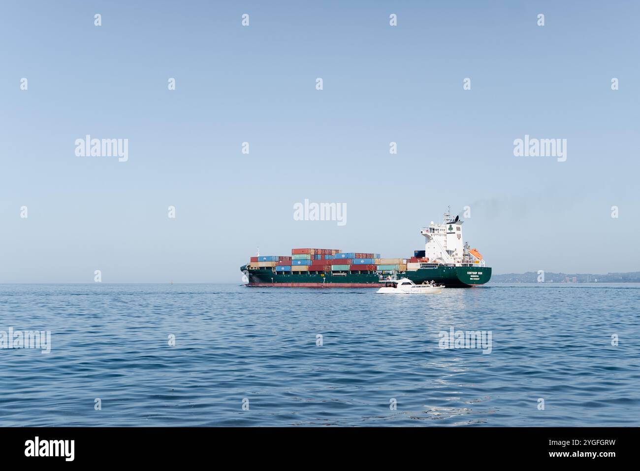 A cargo ship in the open sea under a clear sky. A container ship loaded ...