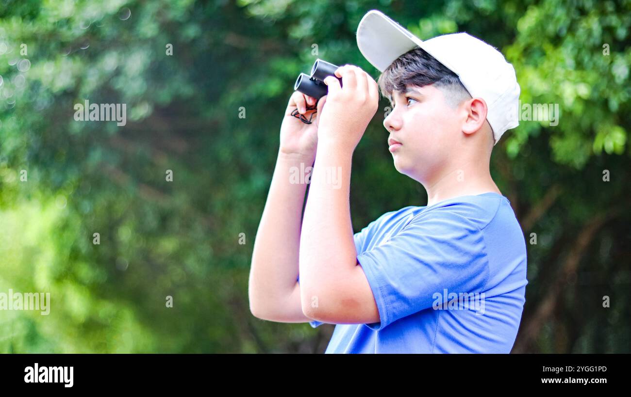 Asian boy using a binocular to do bird watching in the local park to ...