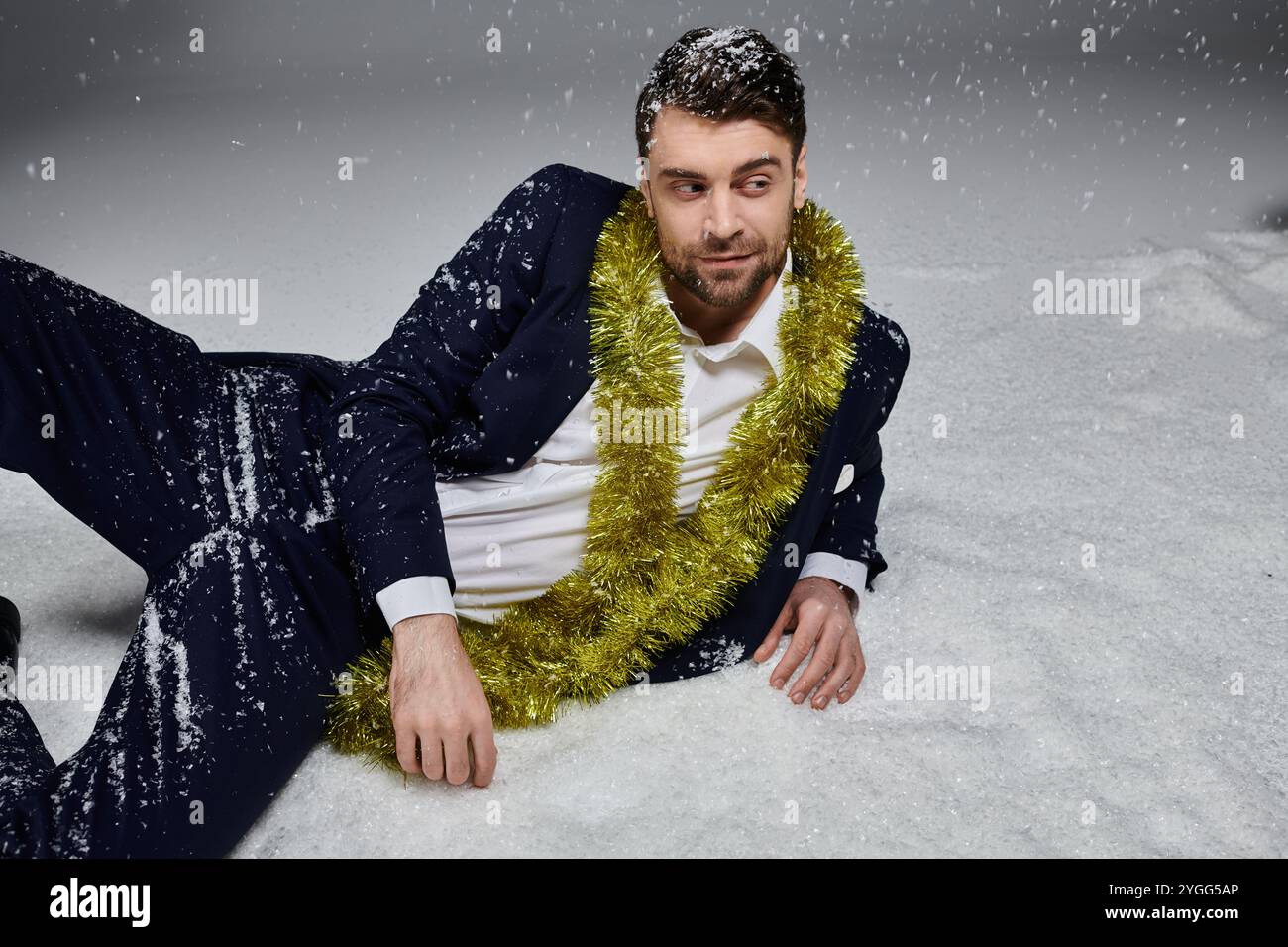 A handsome young man enjoys a playful moment in the snow while dressed ...