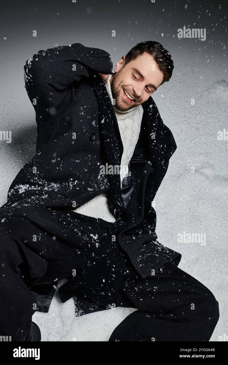 A handsome young man enjoys the snow as he laughs and plays while ...