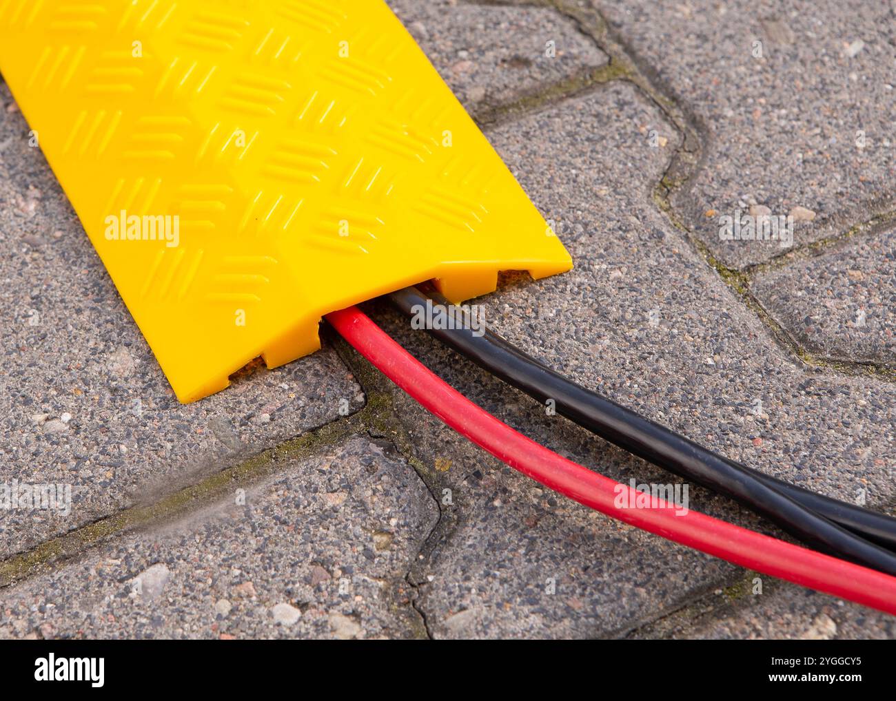 Yellow Cable Protector on Paved Surface Stock Photo - Alamy