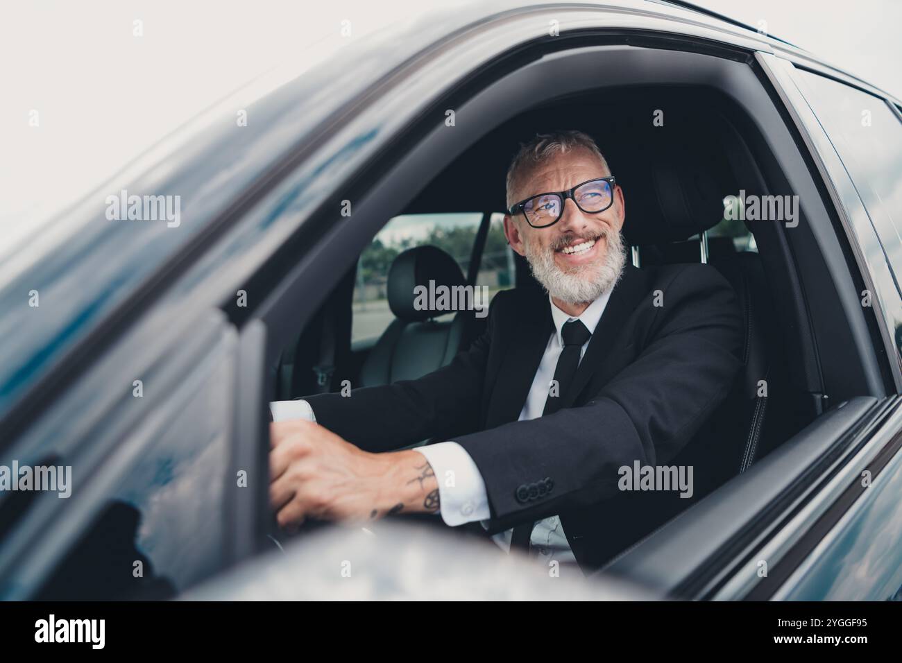 Confident mature businessman driving car with joy and looking towards a ...