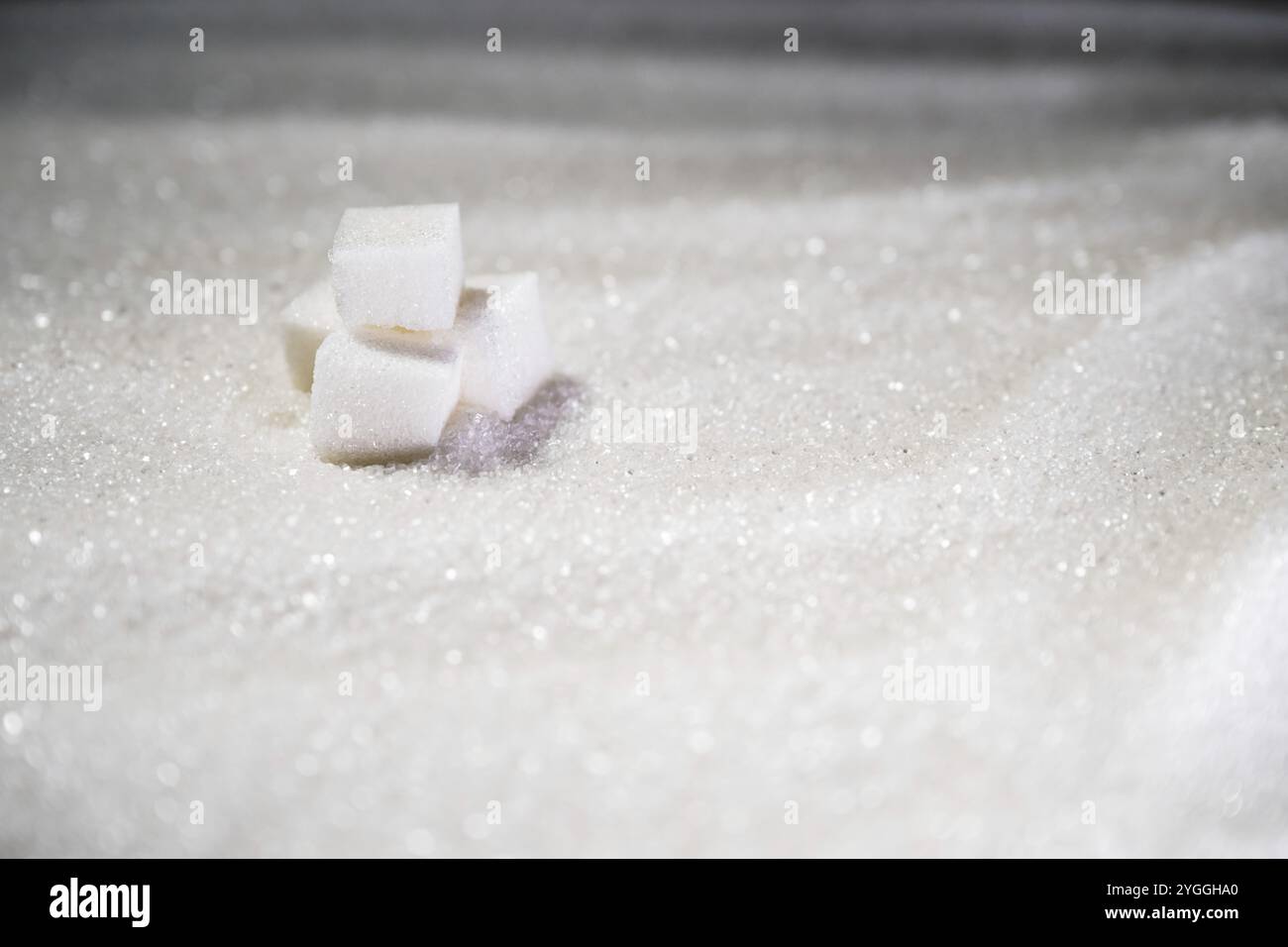 Sugar cubes on a pile of white refined granulated sugar, close up ...