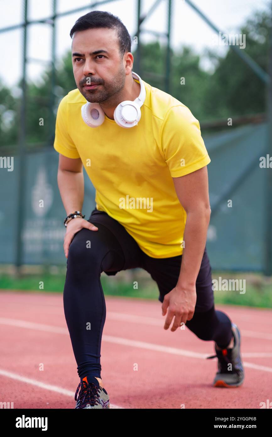 Active sports enthusiast in wireless headphones prepares leg muscles ...