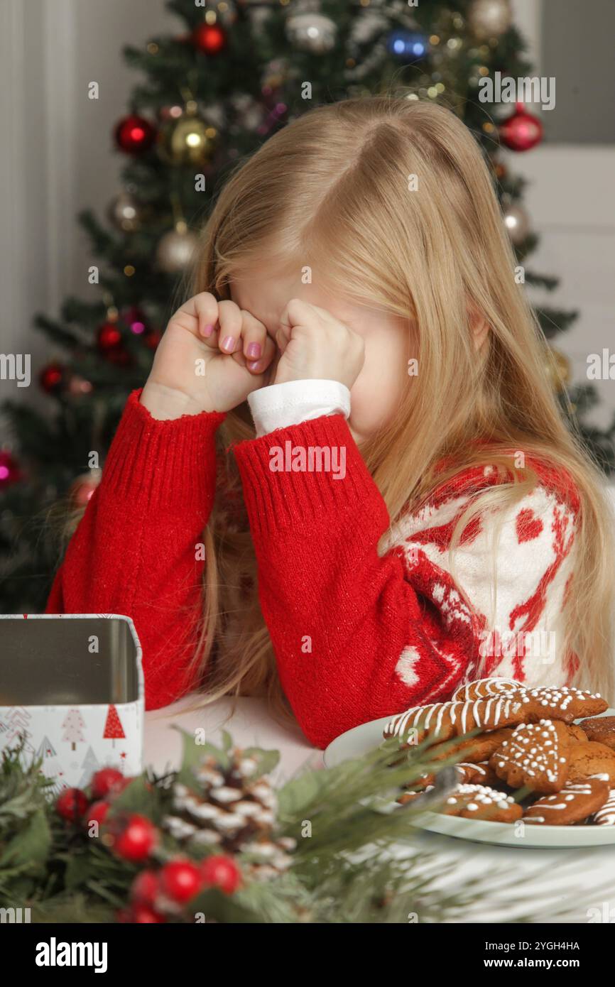 Sad, frustrated little girl in Christmas outfit and Santa hat sitting ...