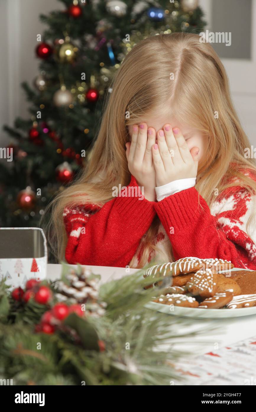 Sad, frustrated little girl in Christmas outfit and Santa hat sitting ...