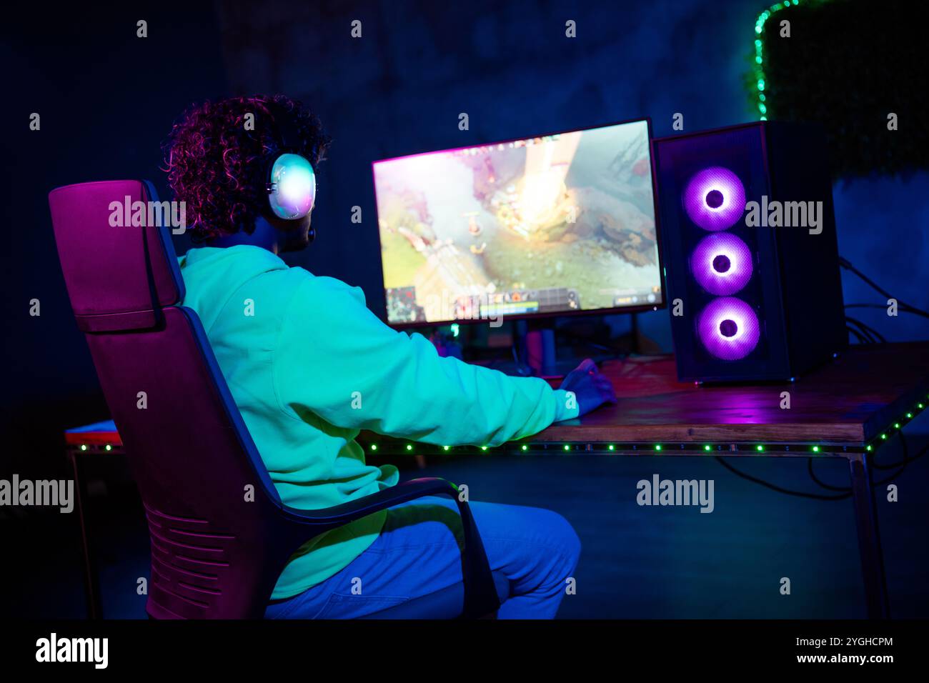 Photo of cute young guy bck view play gamer computer purple blue neon ...