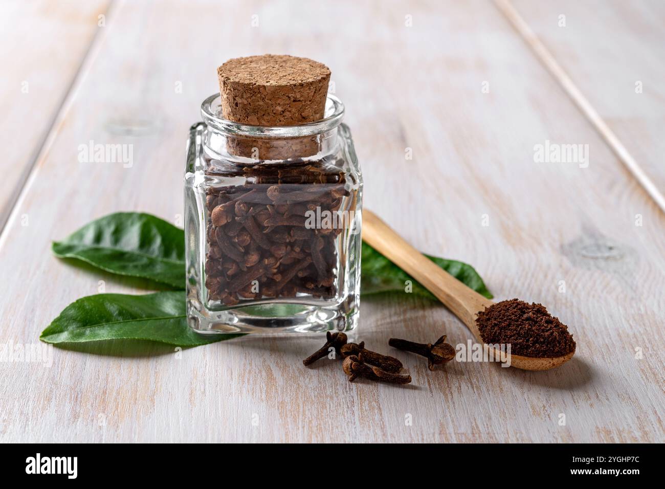 Whole and ground clove buds over white wooden background. Glass jar ...