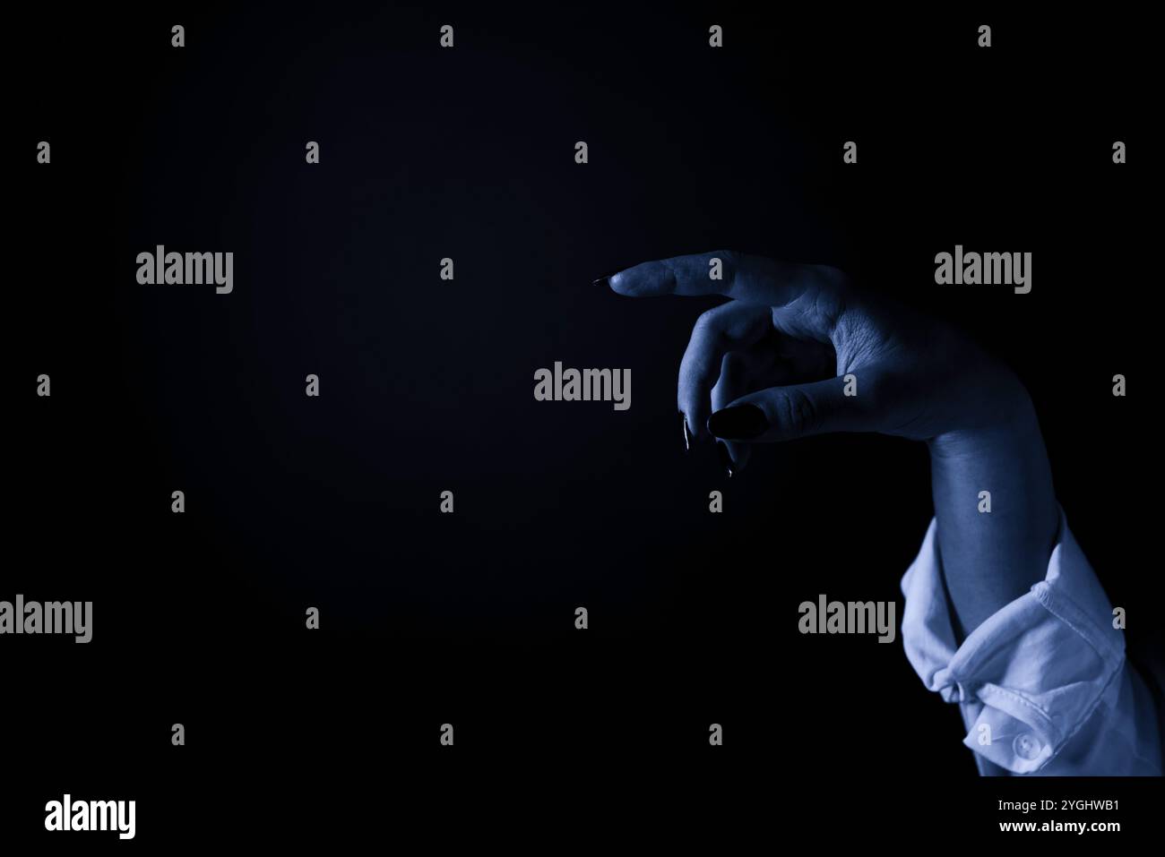 A hand pointing to something in the dark. The hand is covered in black ...