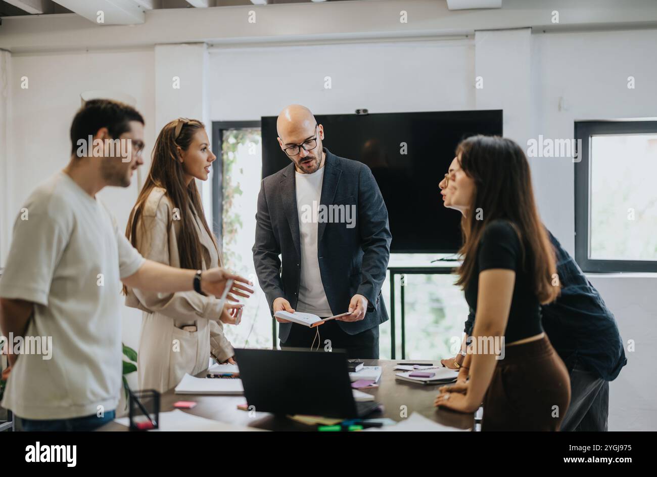 Group of students collaborating with professor on project in classroom ...