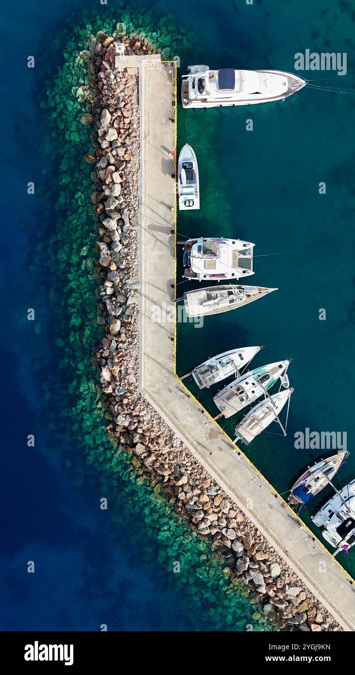 Aerial view of luxury yachts and boats moored along curved stone ...