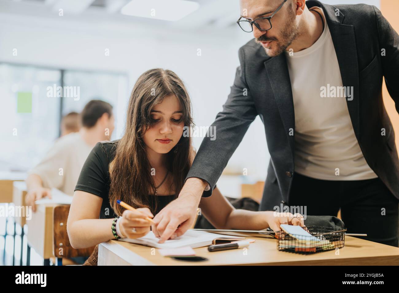 Teacher assisting high school student during classroom lesson Stock ...
