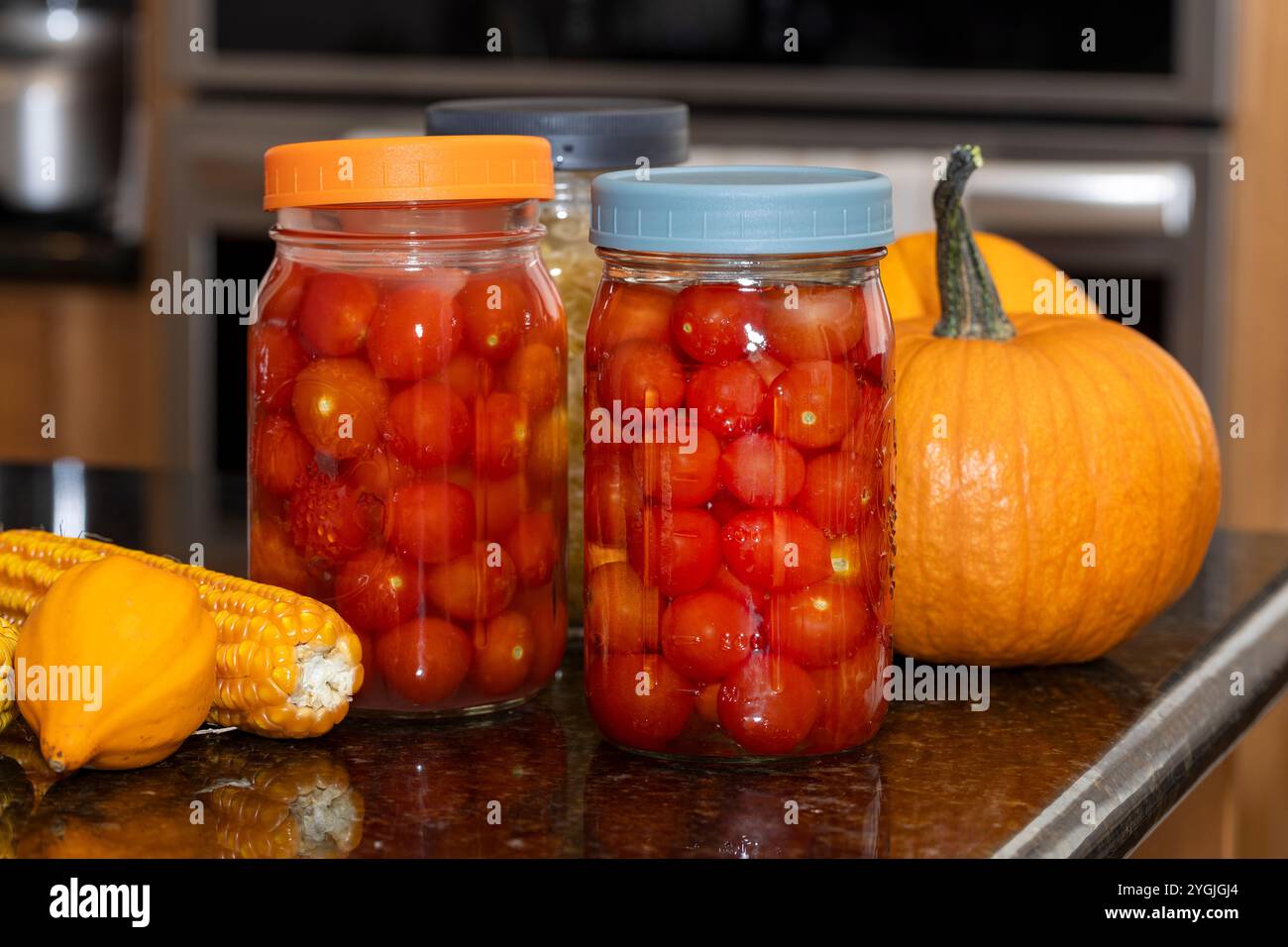 Cherry tomatoes and cabbage being fermented in mason jars on a kitchen ...