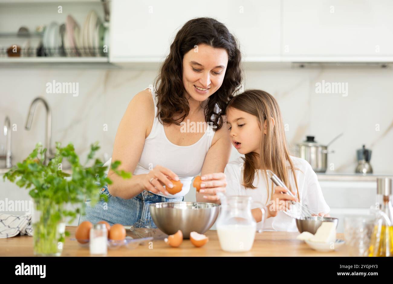 Smiling mother daughter breaks eggs hi-res stock photography and images ...