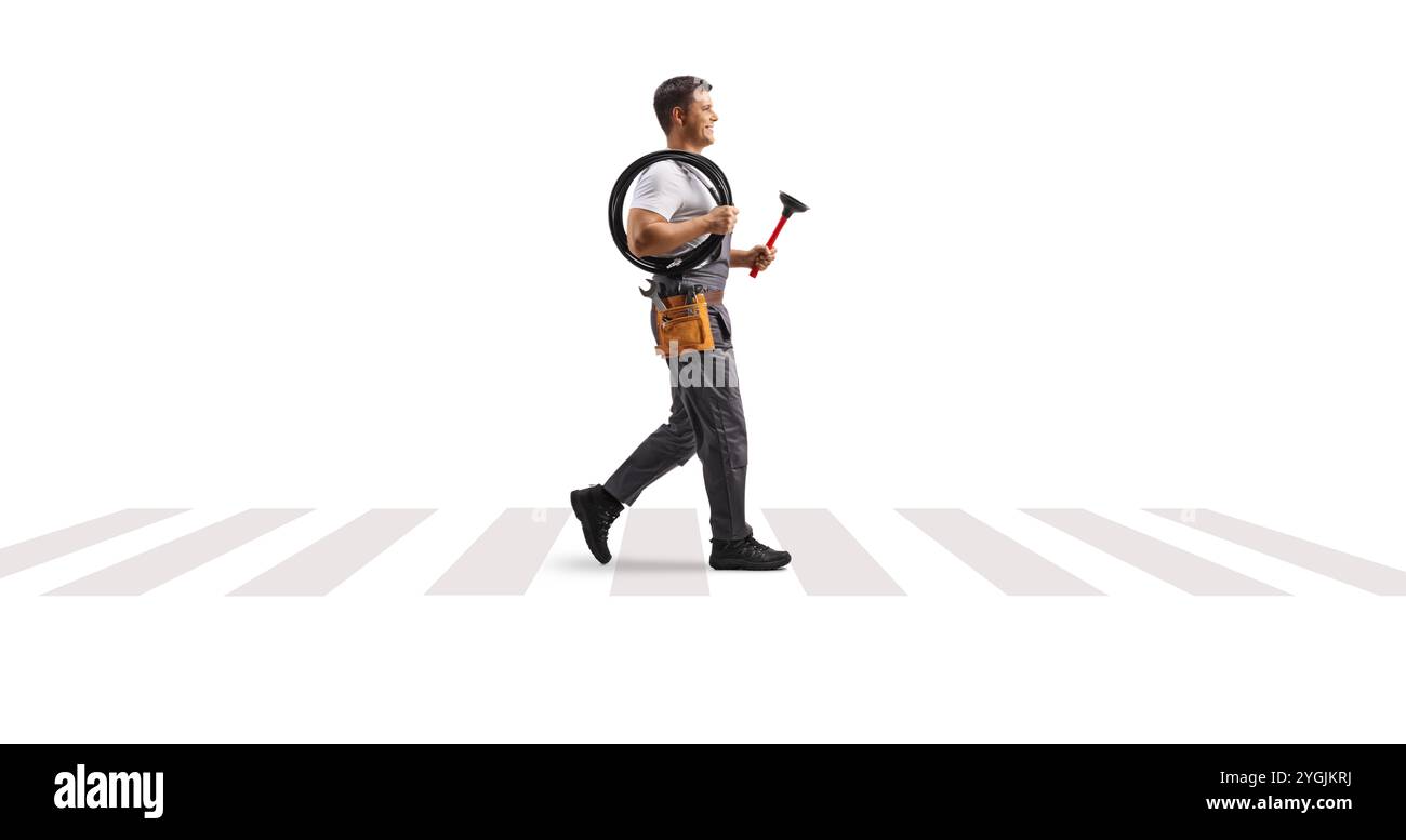 Plumber walking at a pedestrian crossing with a plunger and drain snake ...