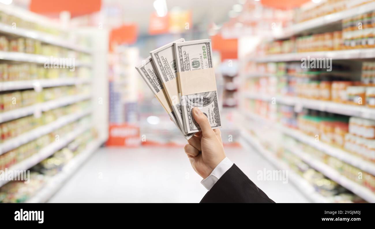 Male hand holding stacks of money inside a supermarket Stock Photo - Alamy