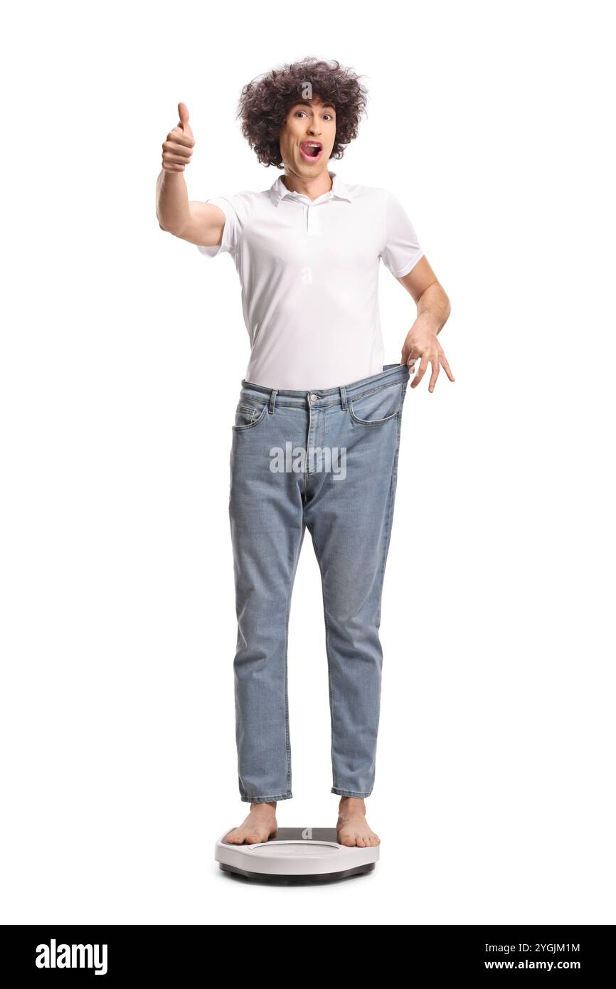 Young man on a weight scale wearing a big sized jeans and gesturing ...