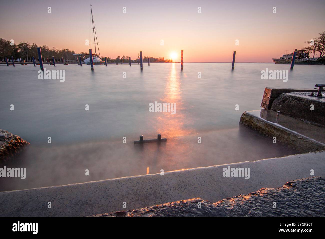 Sunrise on the shore and harbor of a lake in summer. Colorful sky with ...