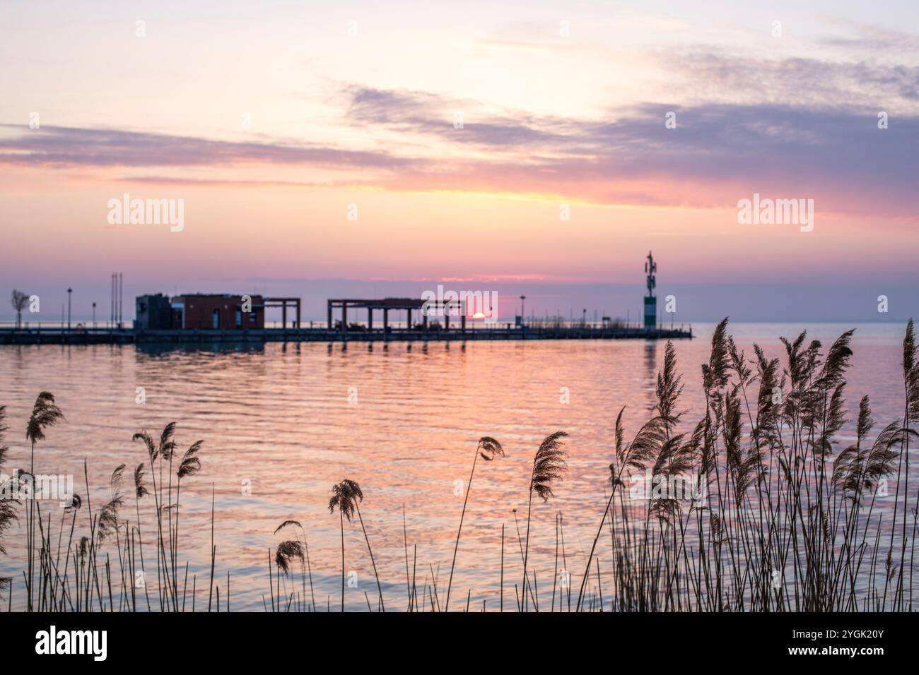 Sunrise on the shore and harbor of a lake in summer. Colorful sky with ...