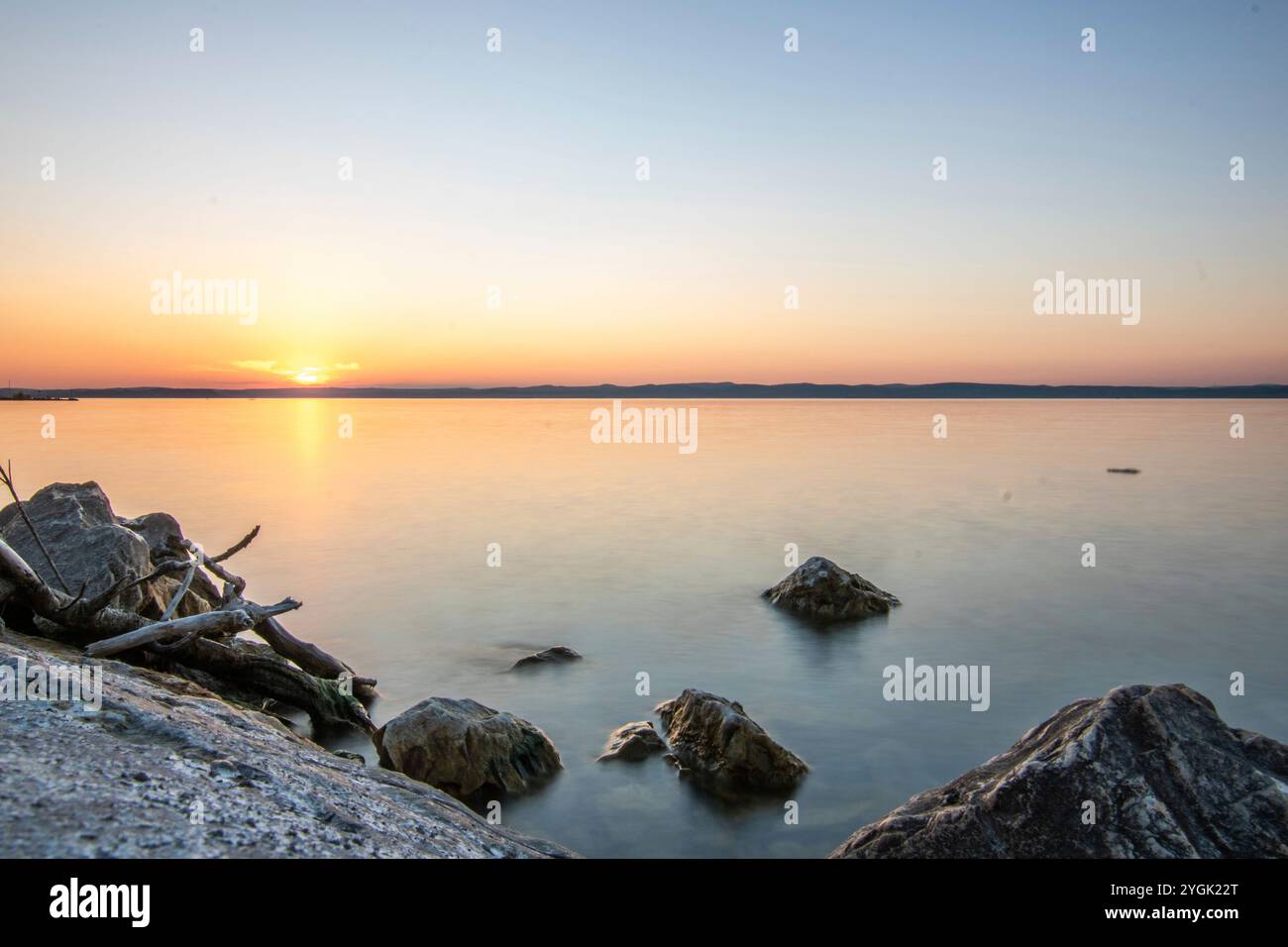 Sunset on the shore of a lake in summer. Colorful sky with a wide view ...