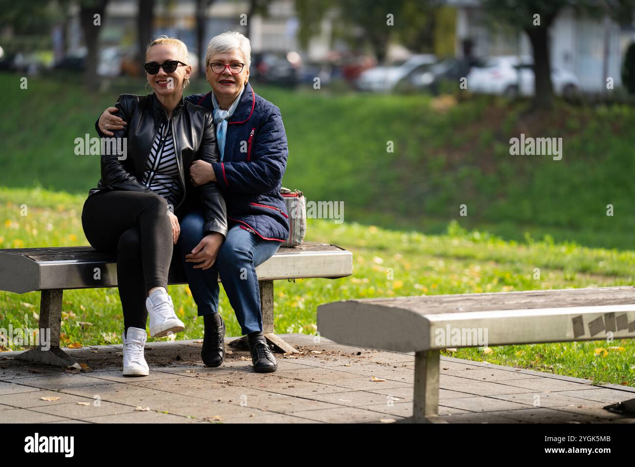 Mother and daughter spend a sunny autumn day in the park, sitting on a ...