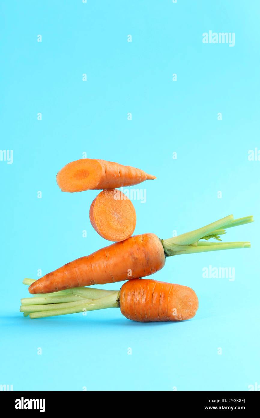Whole and cut fresh carrots on light blue background Stock Photo - Alamy