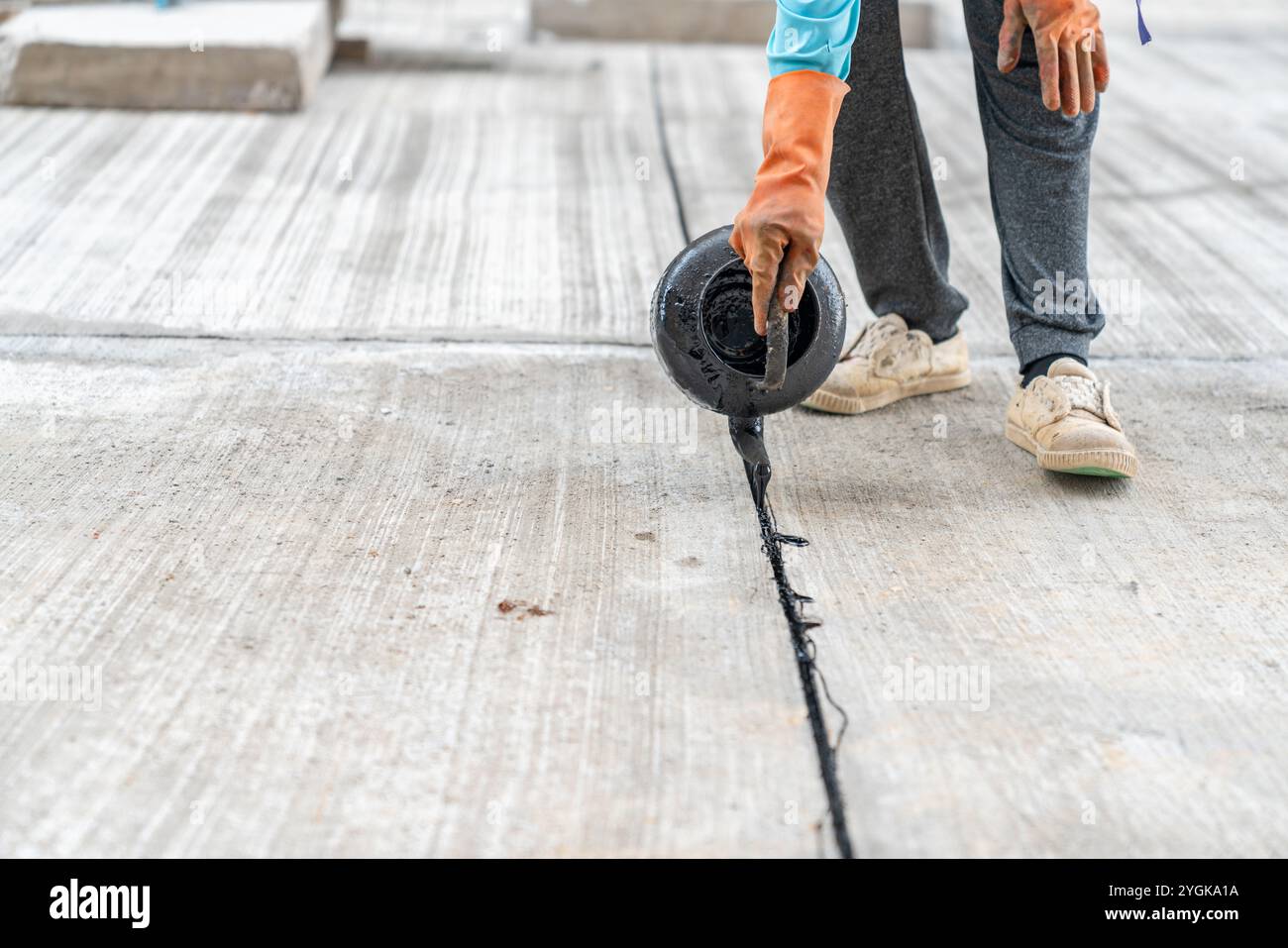 Worker pouring hot melted asphalt between road junction blocks in ...