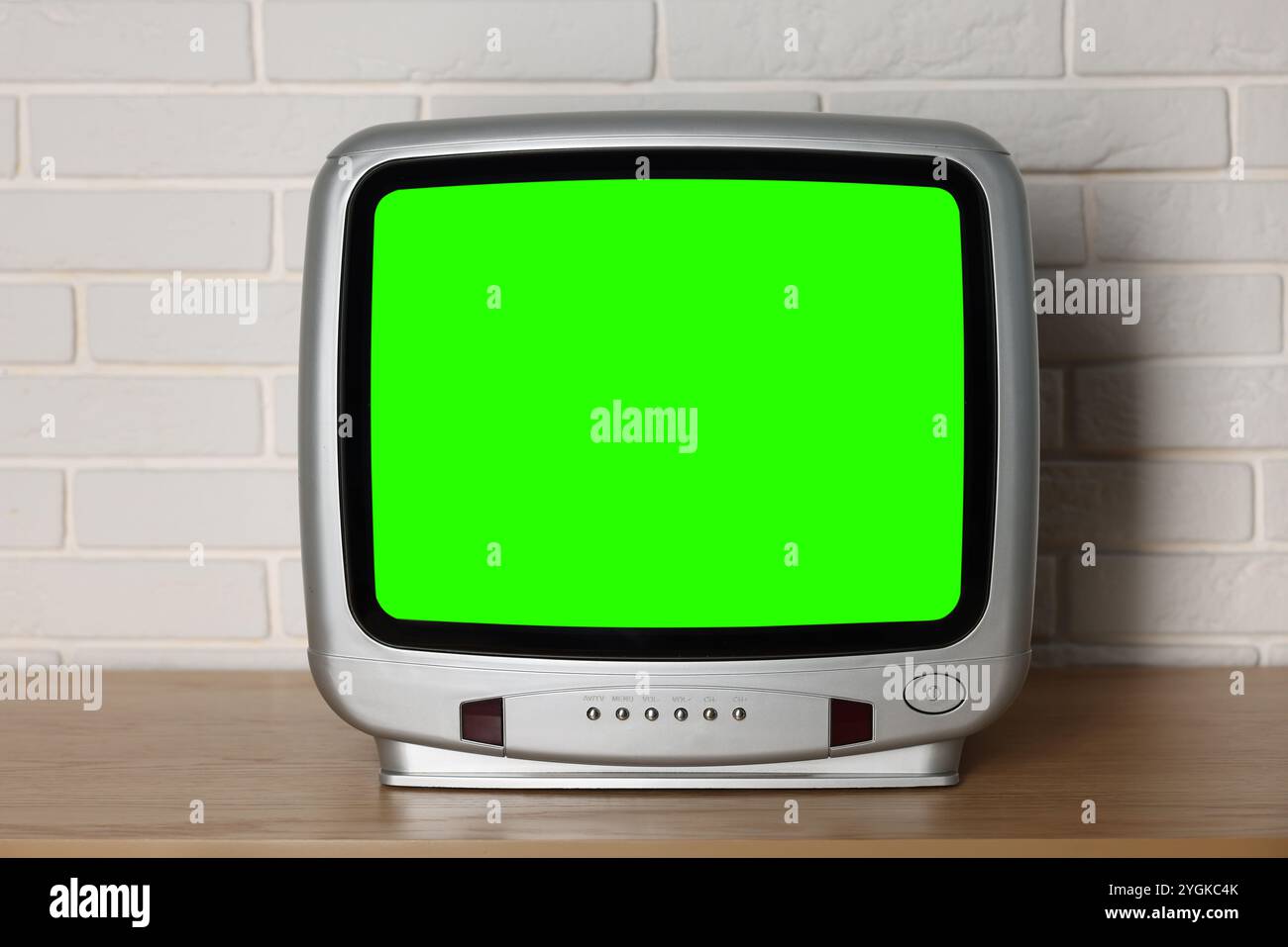 Retro Tv set with green screen on wooden table near white brick wall ...