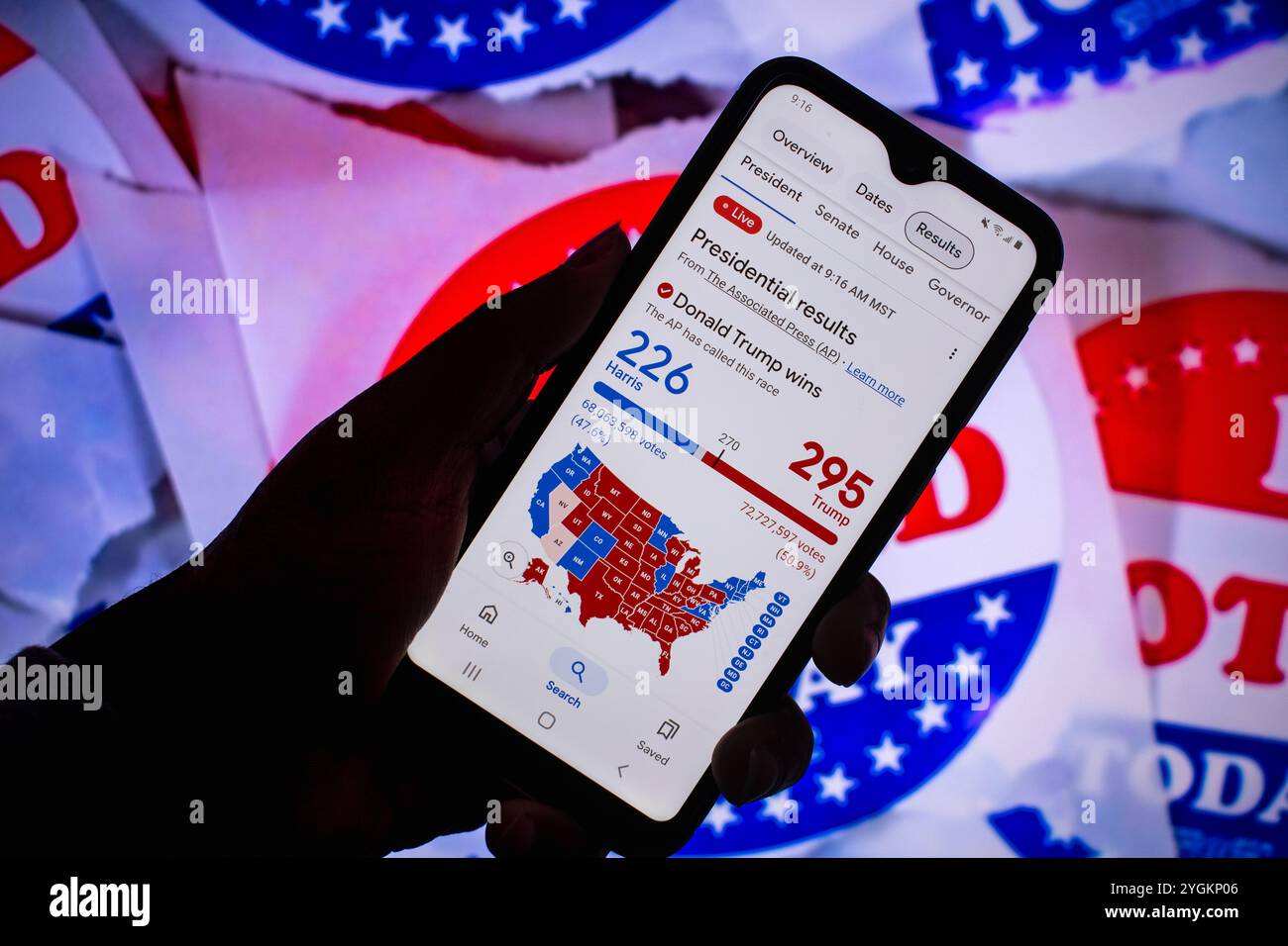 A man holds a smartphone showing the results of the 2024 United States ...