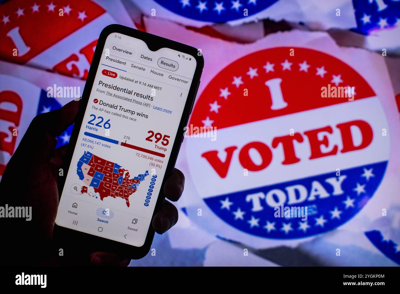 A man holds a smartphone showing the results of the 2024 United States ...