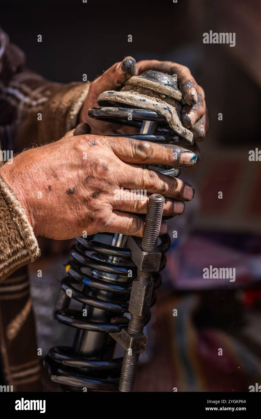 The calloused hands of a mechanic assembling compressed coil spring ...