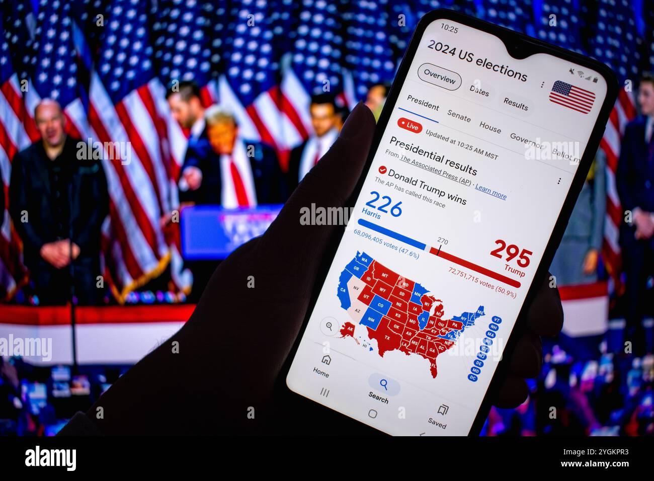 A man holds a smartphone showing the results of the 2024 United States ...