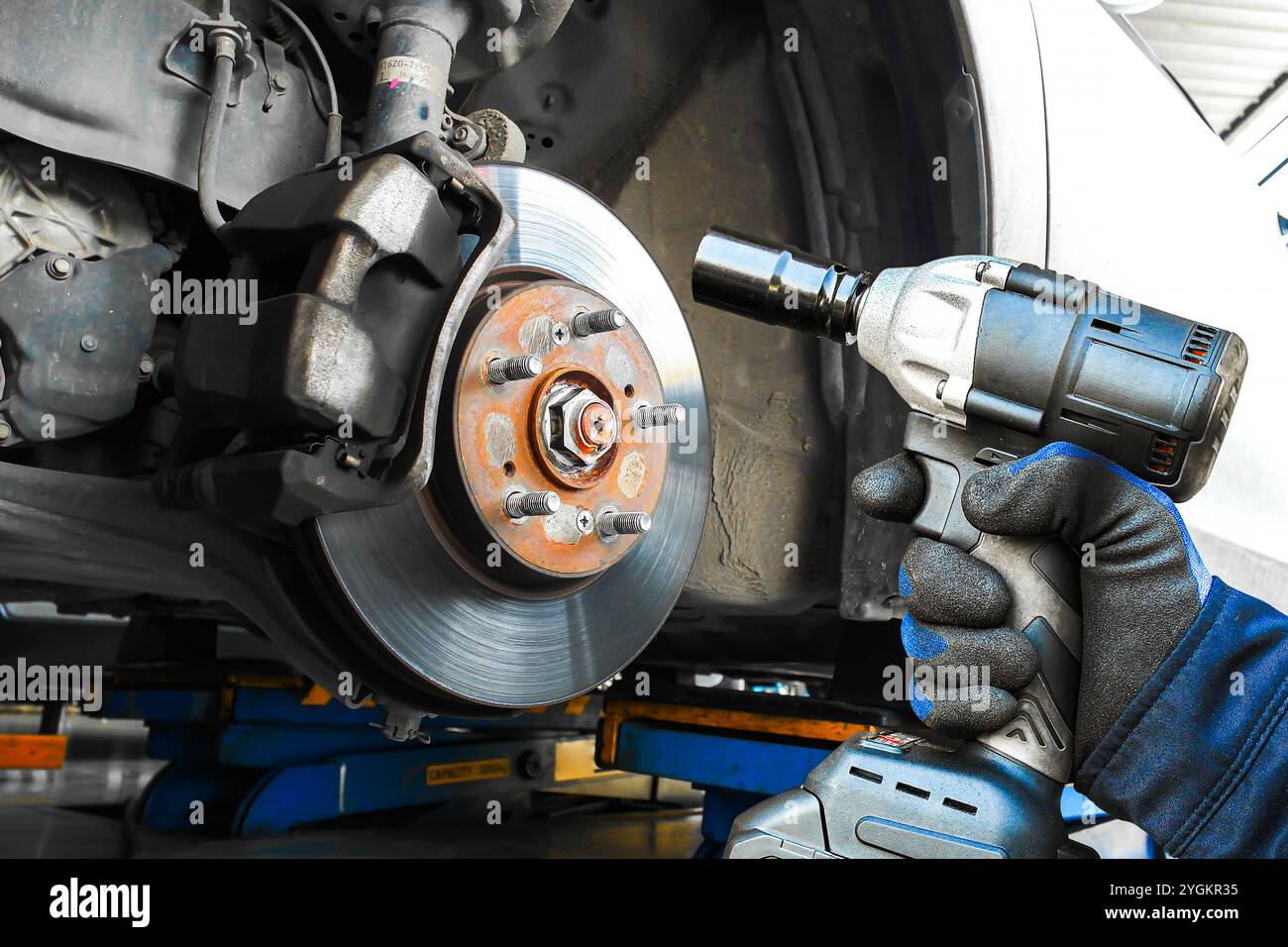 Car brake system repairing , close up of mechanic using impact wrench ...