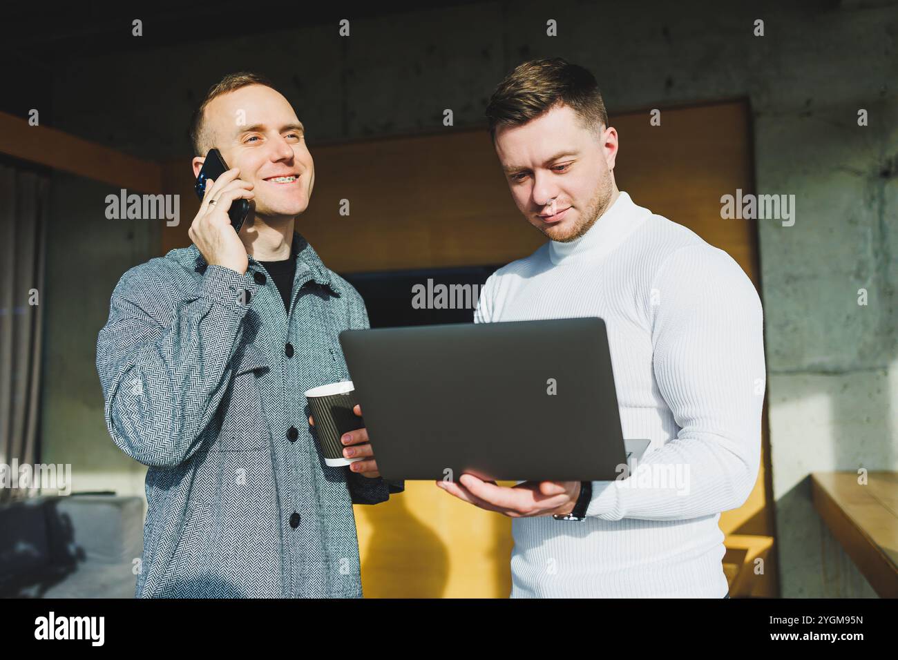 Work of two male colleagues standing in office together while ...