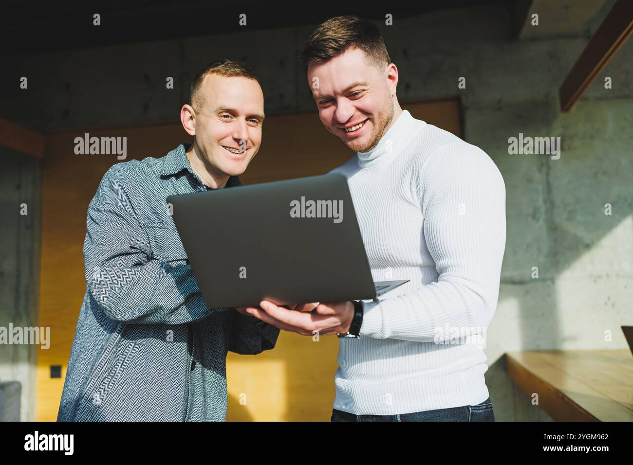 Work of two male colleagues standing in office together while ...