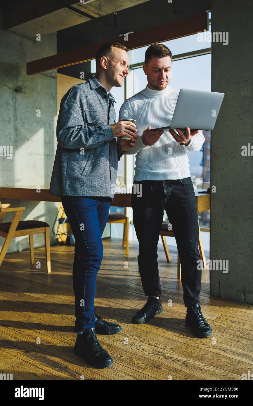 Work of two male colleagues standing in office together while ...