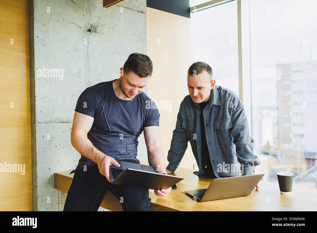 Work of two colleagues sitting together while exchanging ideas with a ...